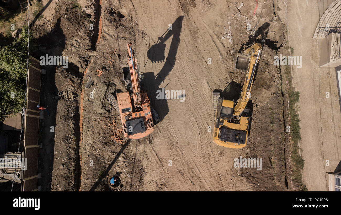 Heavy equipment is grading the land, moving and flattening out red clay ...