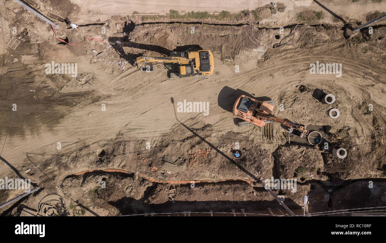 Heavy equipment is grading the land, moving and flattening out red clay ...