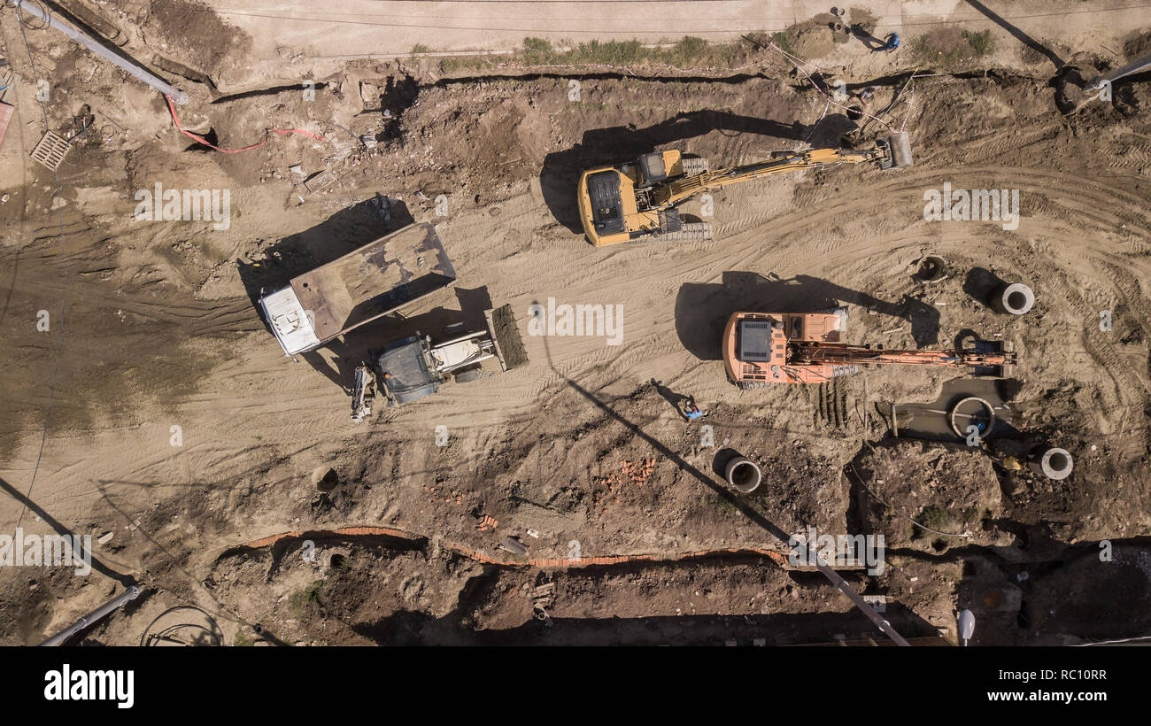 Heavy equipment is grading the land, moving and flattening out red clay ...