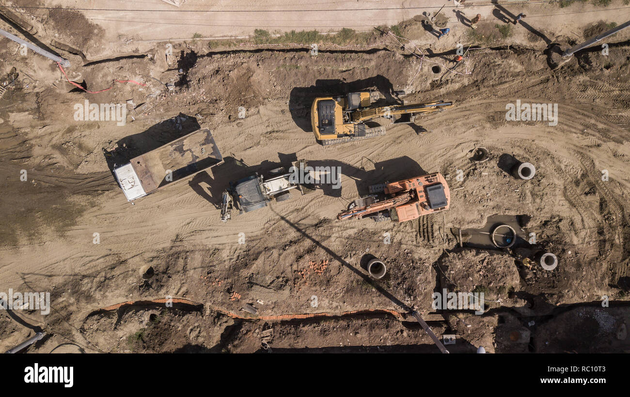 Heavy equipment is grading the land, moving and flattening out red clay ...