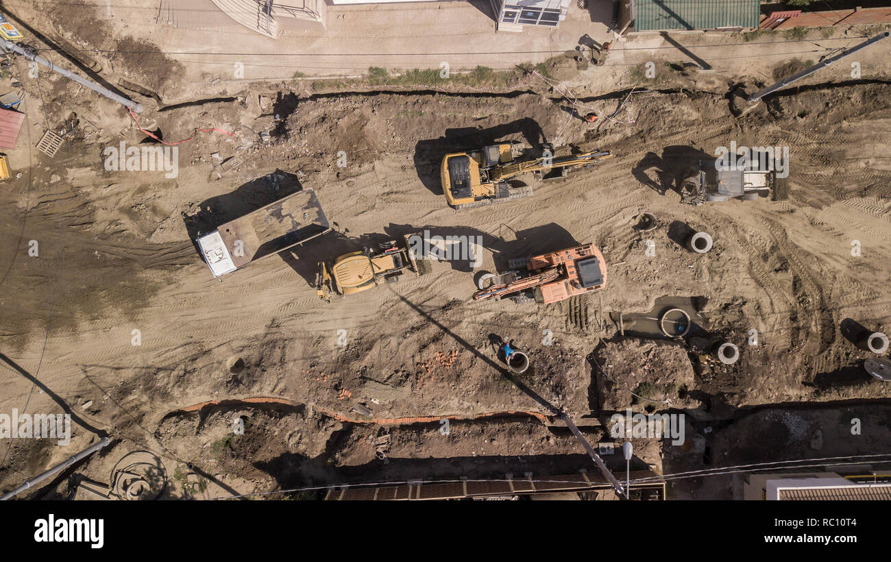 Heavy equipment is grading the land, moving and flattening out red clay ...