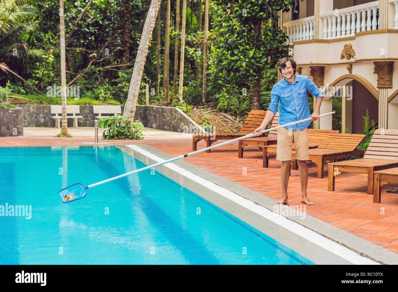 Cleaner of the swimming pool . Man in a blue shirt with cleaning ...