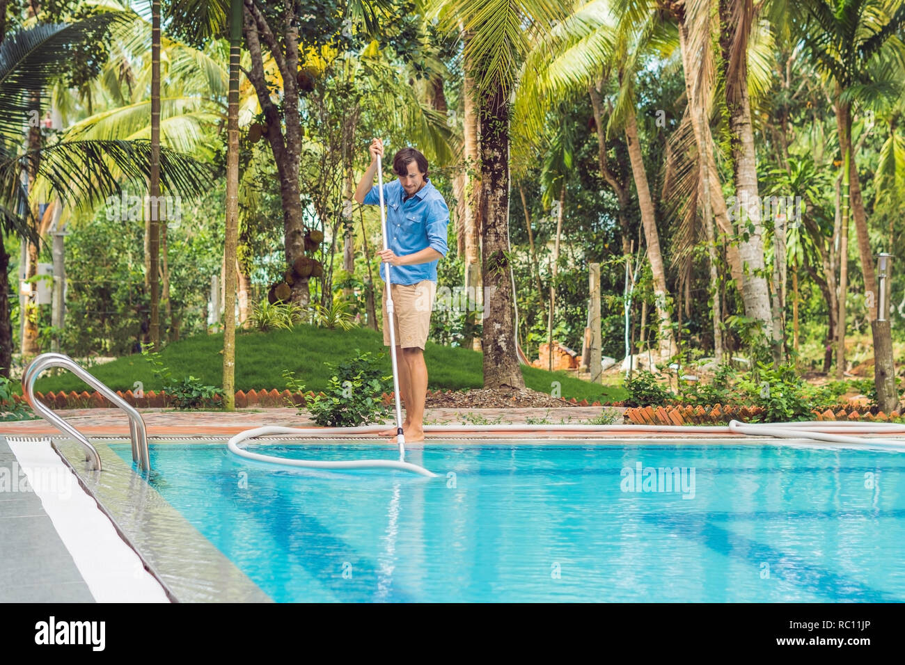 Cleaner of the swimming pool . Man in a blue shirt with cleaning ...