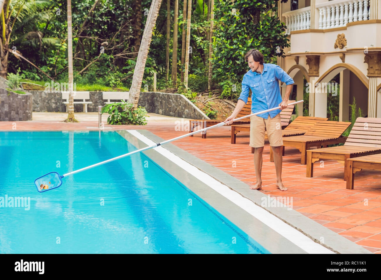 Cleaner of the swimming pool . Man in a blue shirt with cleaning ...