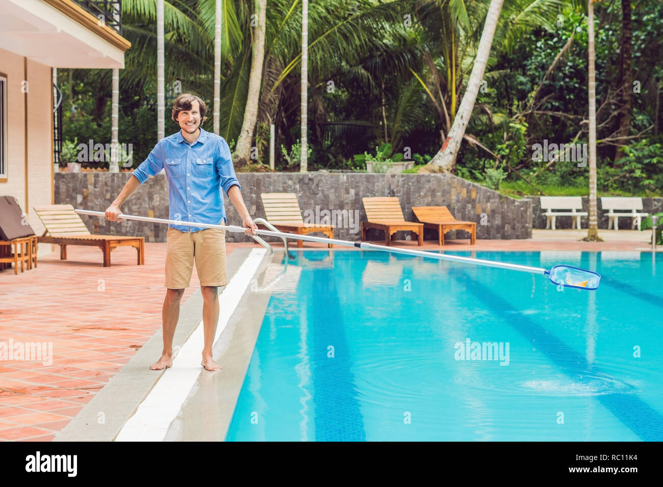 Cleaner of the swimming pool . Man in a blue shirt with cleaning ...