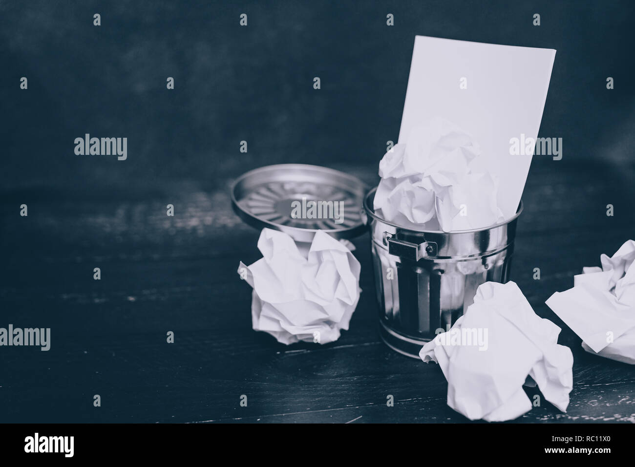 garbage bin on desk setting with notepad and scrunched paper balls ...