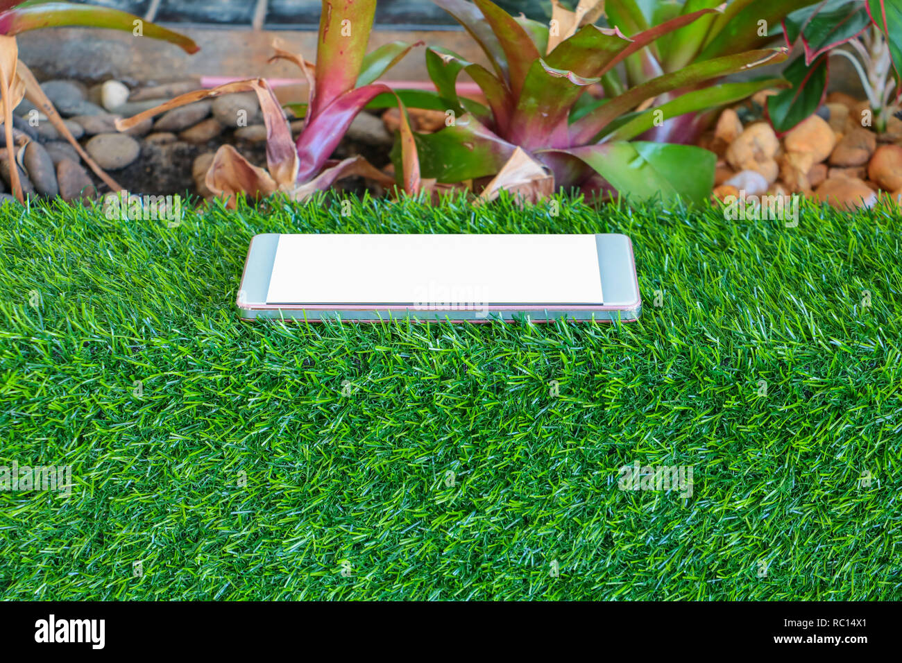 Mobile phone on artificial grass green background Stock Photo - Alamy