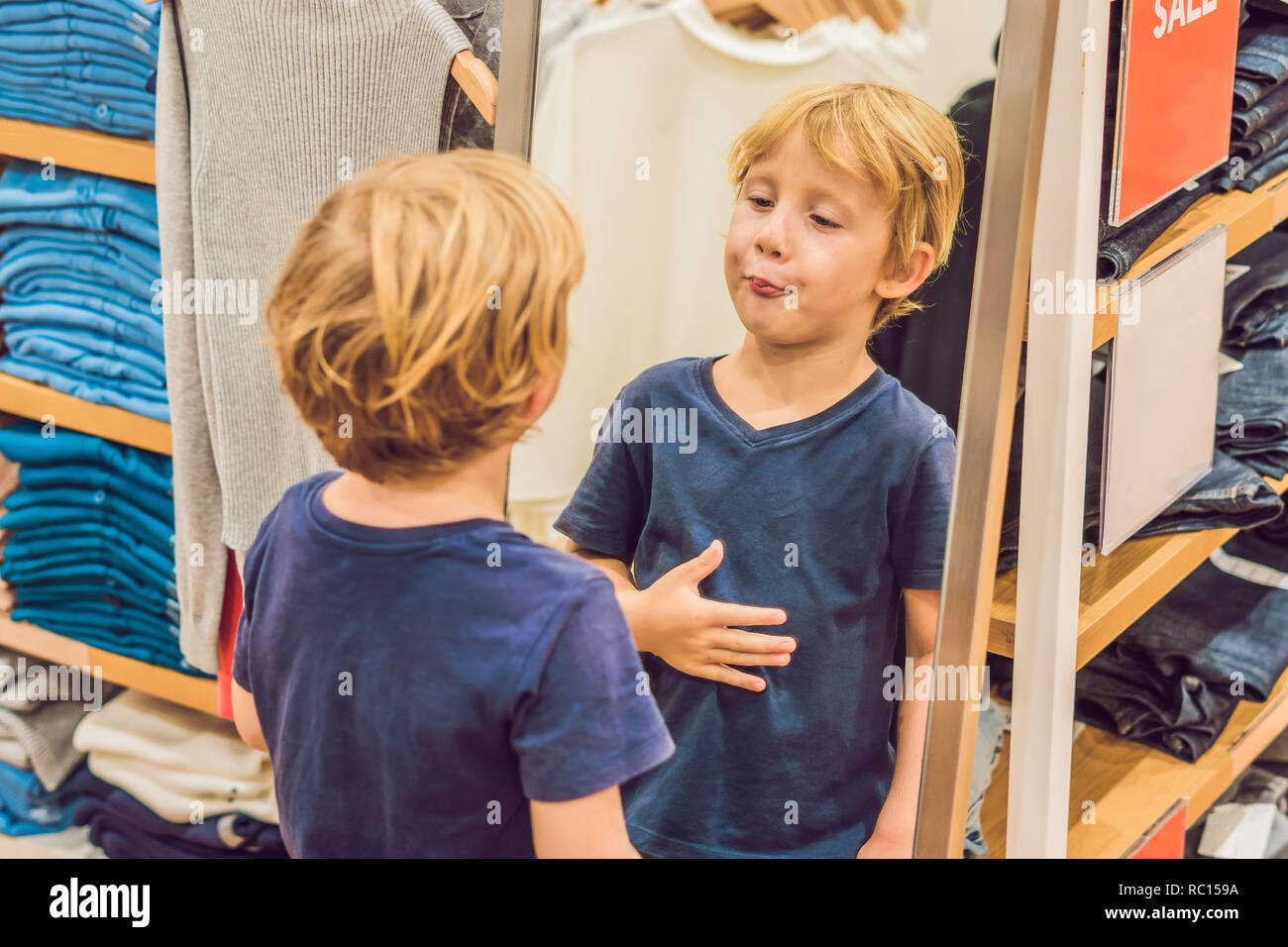 The boy tries on clothes in the childrens clothing store Stock Photo ...