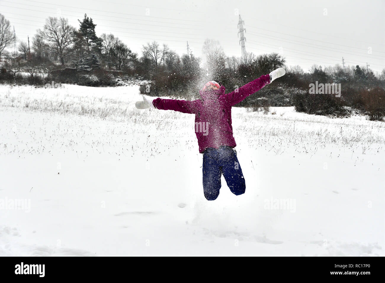 The smiling girl jumps and falls into the snow Stock Photo - Alamy