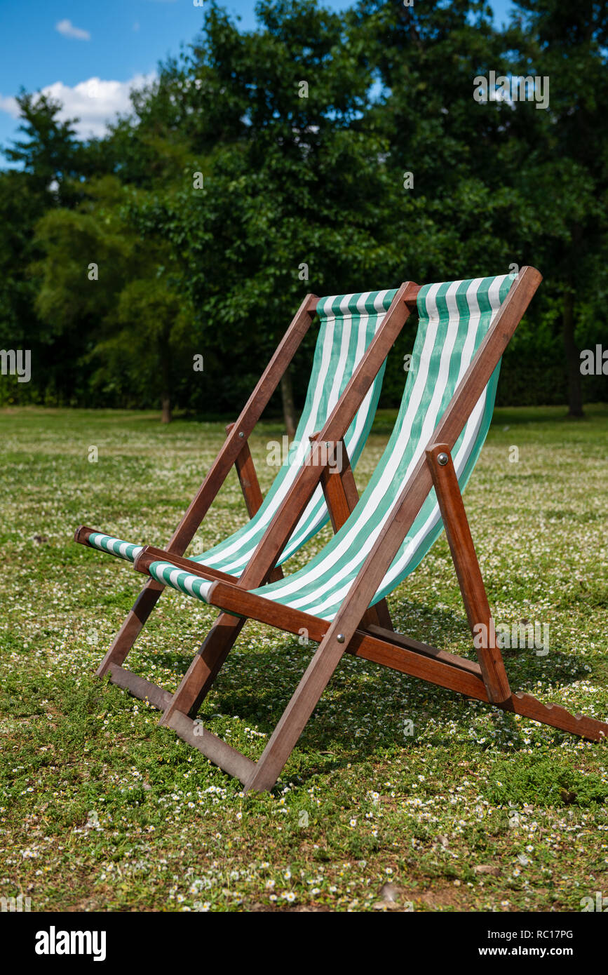 Striped deck chairs on the english lawn with forest trees on the ...