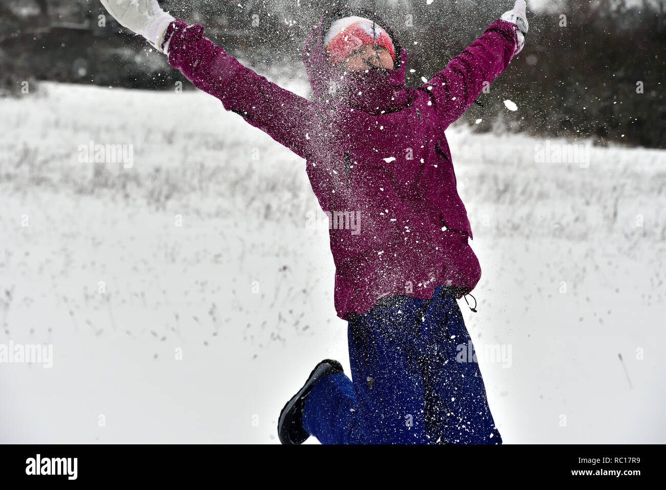 The smiling girl jumps and falls into the snow Stock Photo - Alamy
