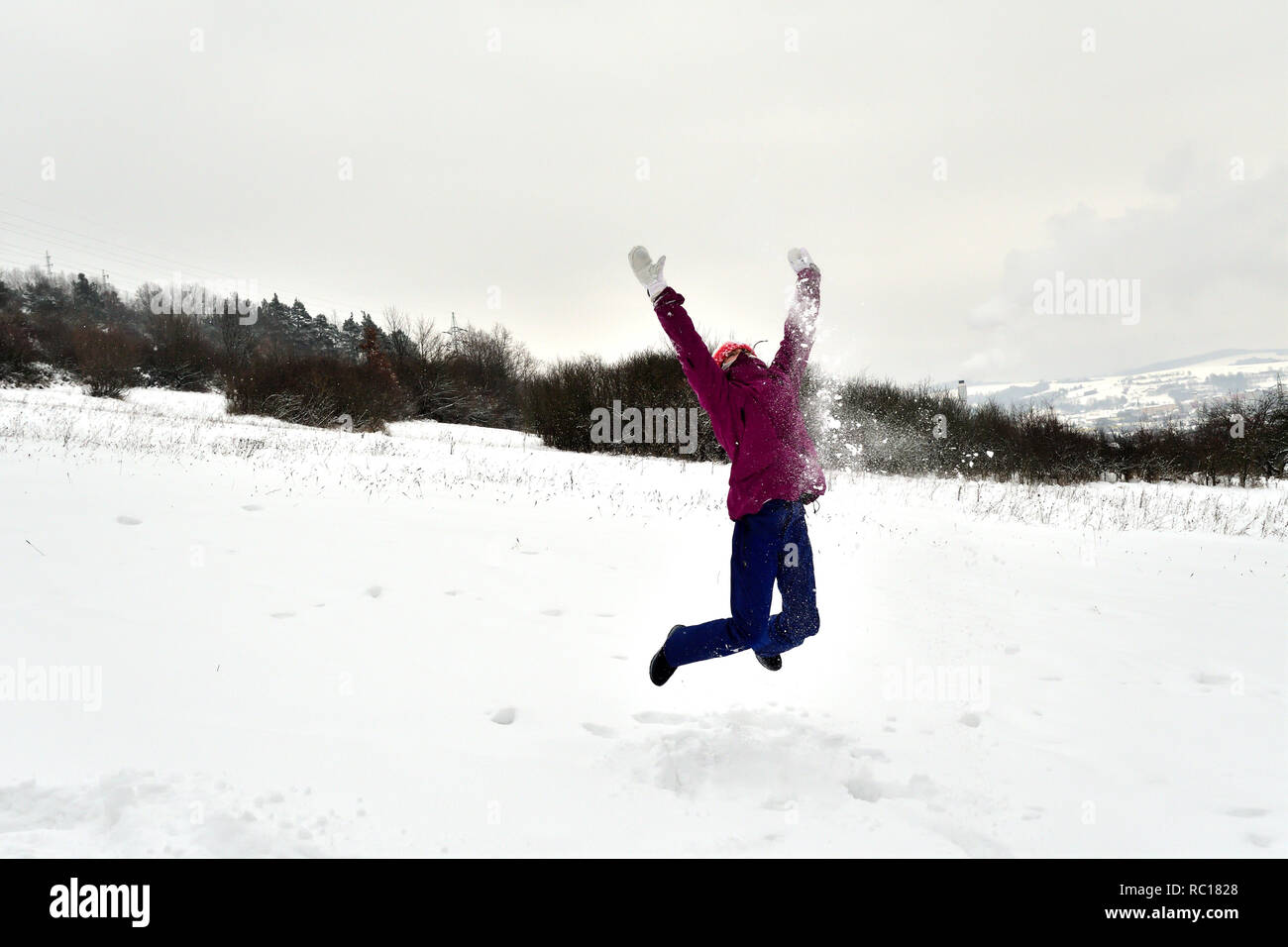 The smiling girl jumps and falls into the snow Stock Photo - Alamy
