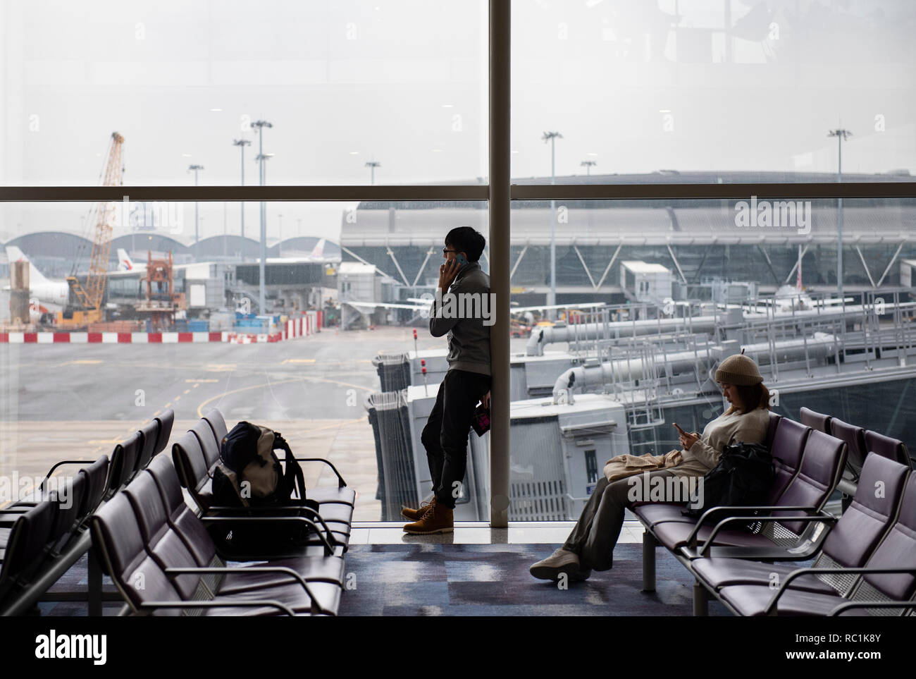 Passengers sitting in waiting area at a boarding gate at Hong Kong International Airport Stock ...
