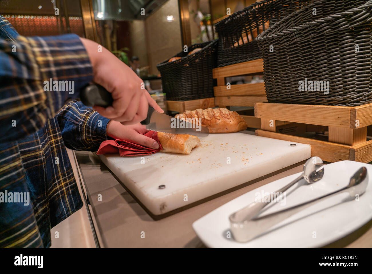 Young woman cutting baguette with a knife Stock Photo - Alamy