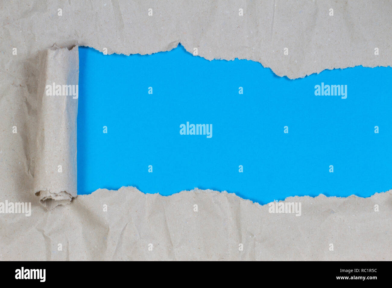 Brown package paper torn to reveal blue background with copy space ...