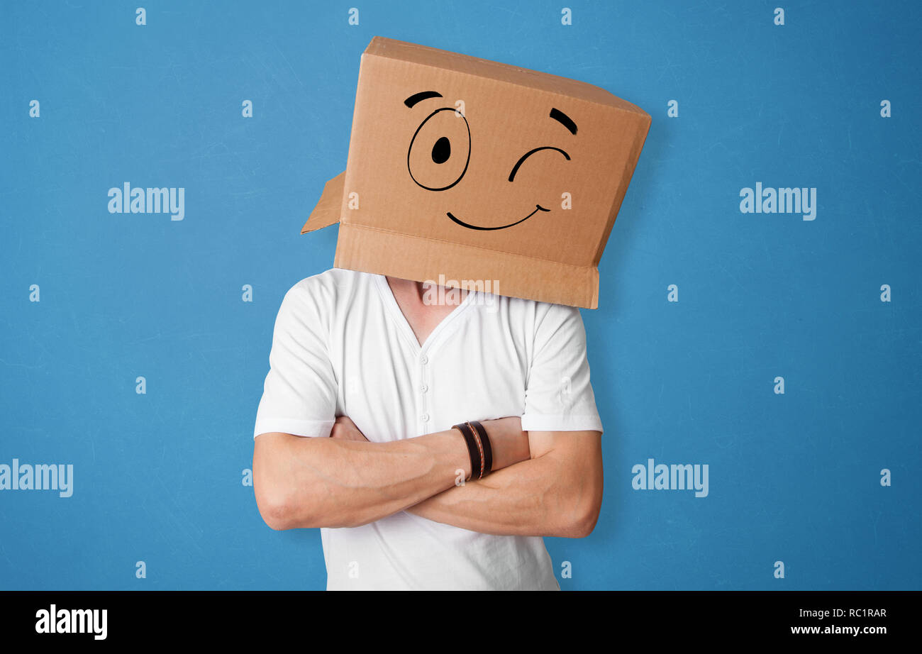 Young man standing and gesturing with a cardboard box on his head with ...