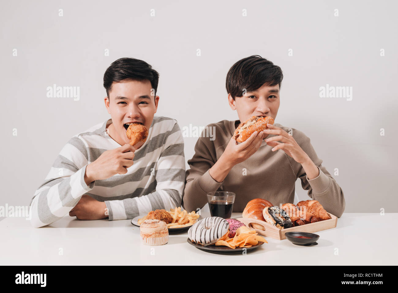 Two friends eating burgers. french fries, having fun and smiling Stock ...