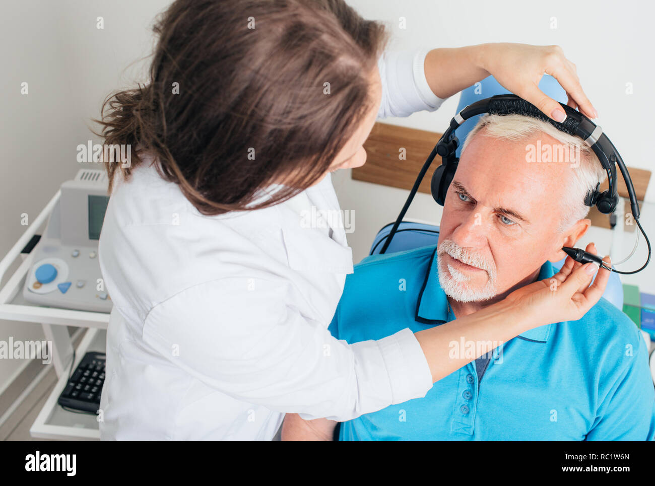 audiologist doing hearing test to a mature man at hearing clinic Stock ...