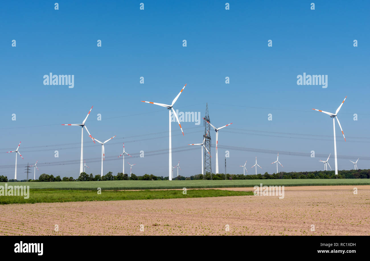 Overhead power lines and modern wind turbines in the fields in Germany ...