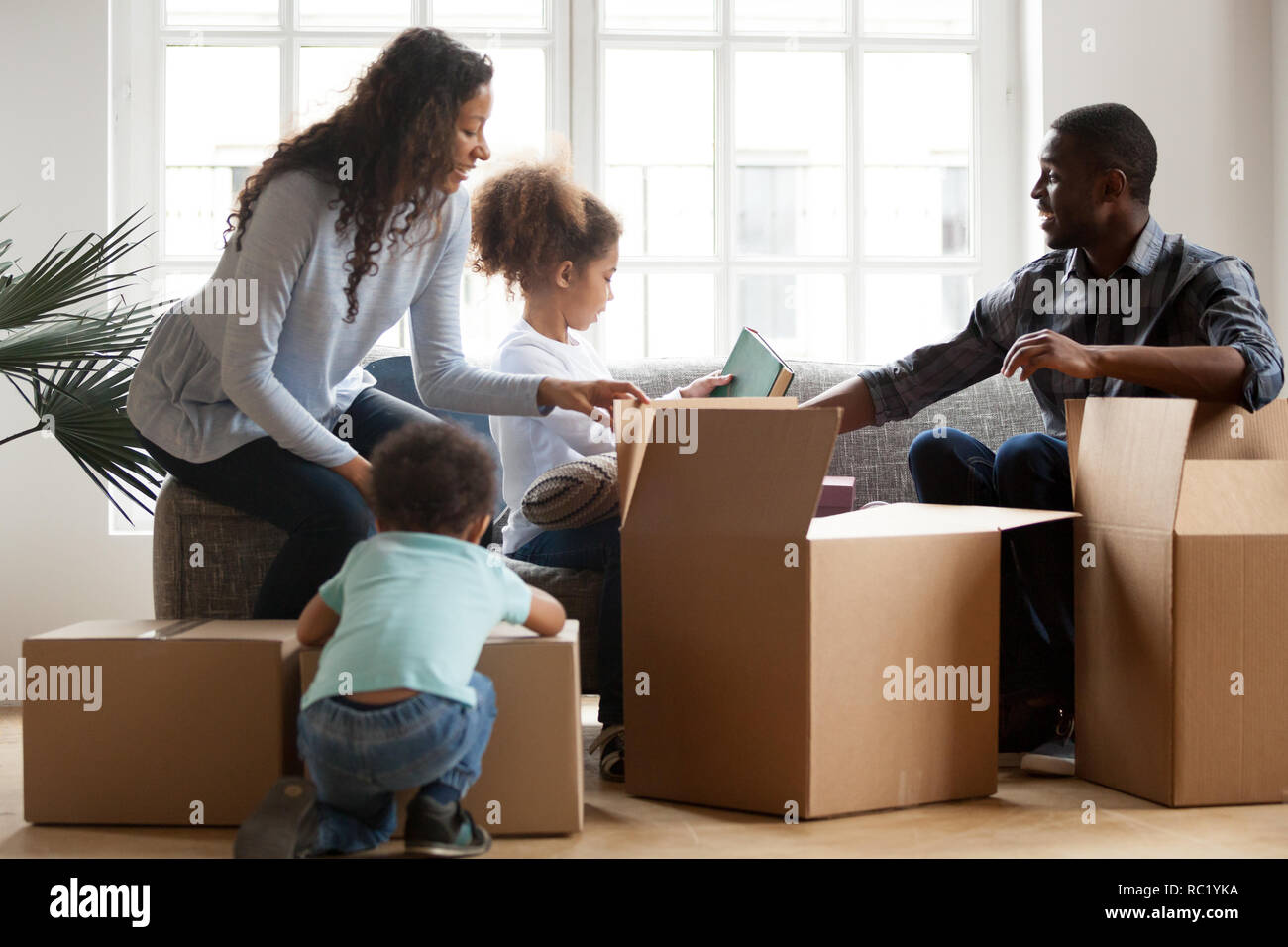 African american kids helping parents unpacking boxes in living Stock ...