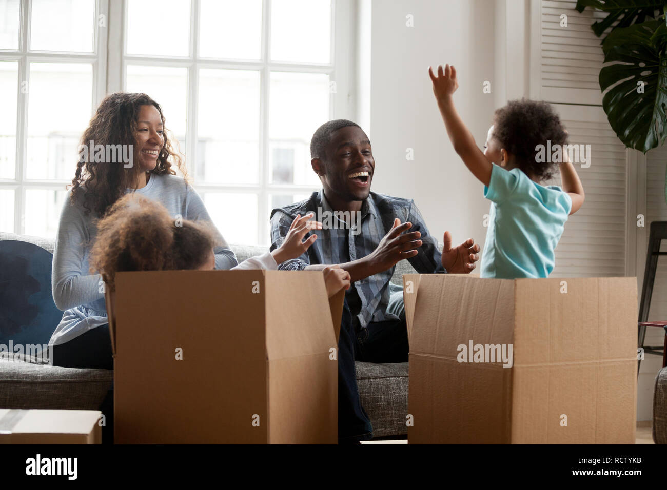Excited mixed-race kids jumping out of box playing with parents Stock ...
