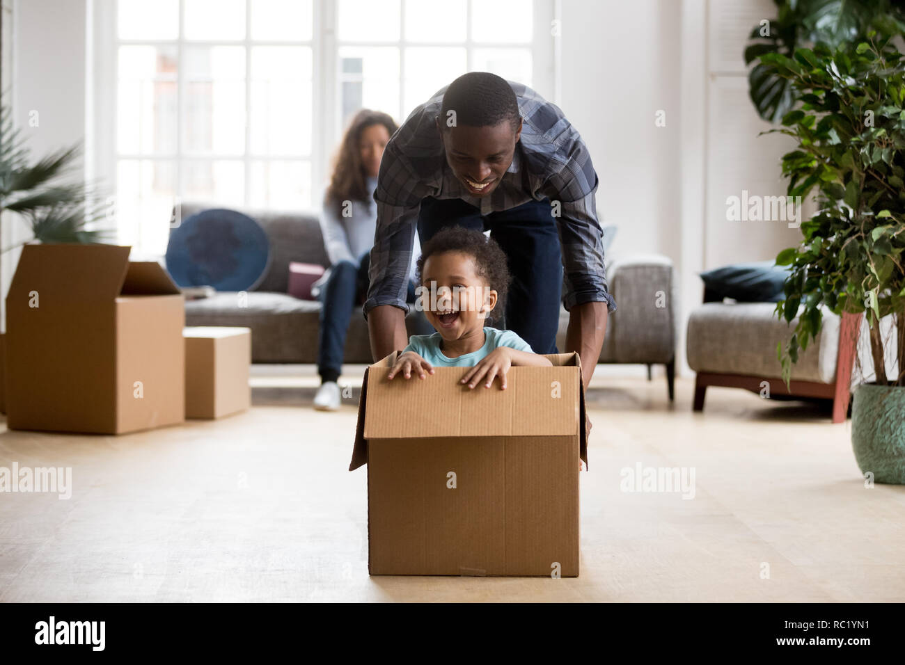 African son laughing excited by riding in box with dad Stock Photo - Alamy
