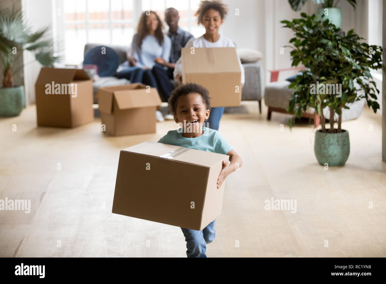 Cute mixed race children enjoying moving day running carrying bo Stock ...