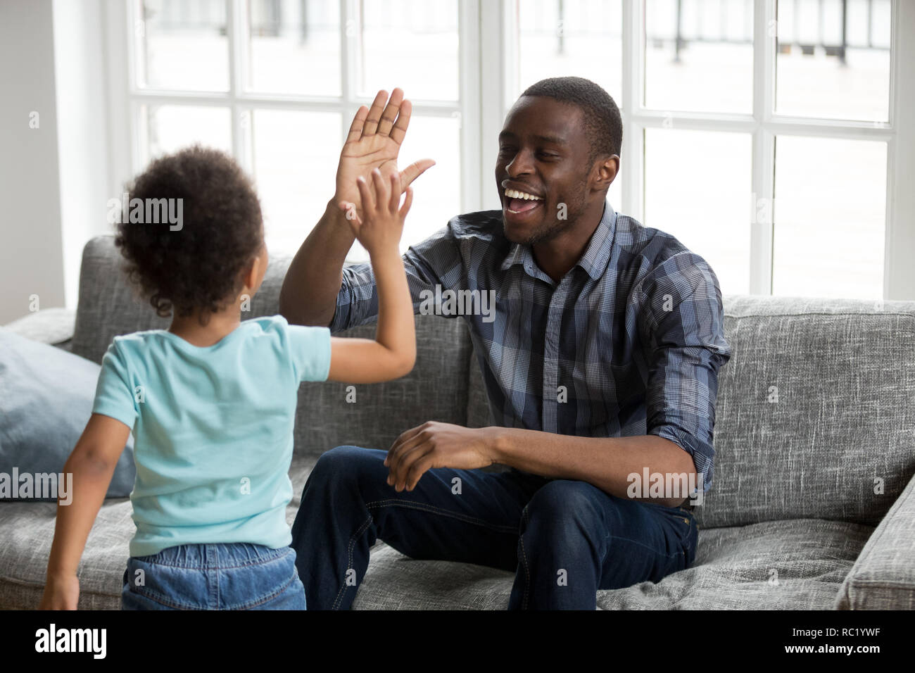 Happy black dad and son giving high-five playing at home Stock Photo ...