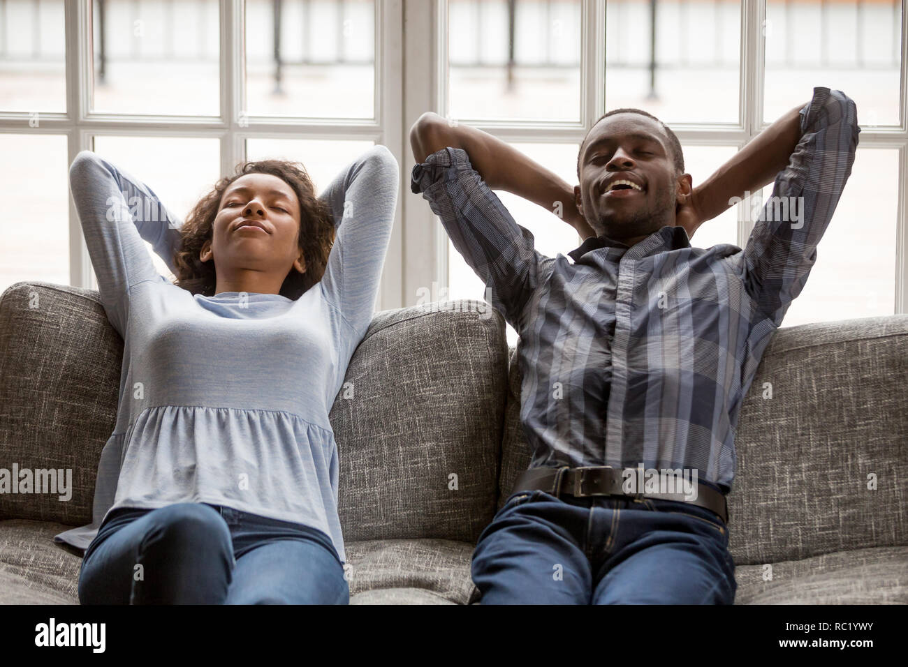African American Millennial Couple Relaxing On Comfortable Sofa Stock