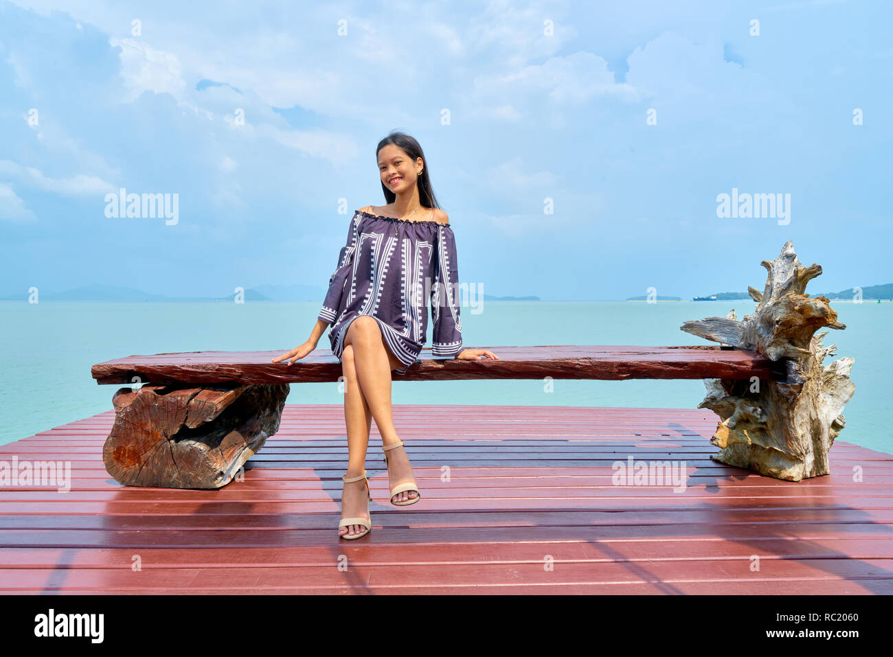 Beautiful woman posing - sitting on bench, looking at camera and happy ...