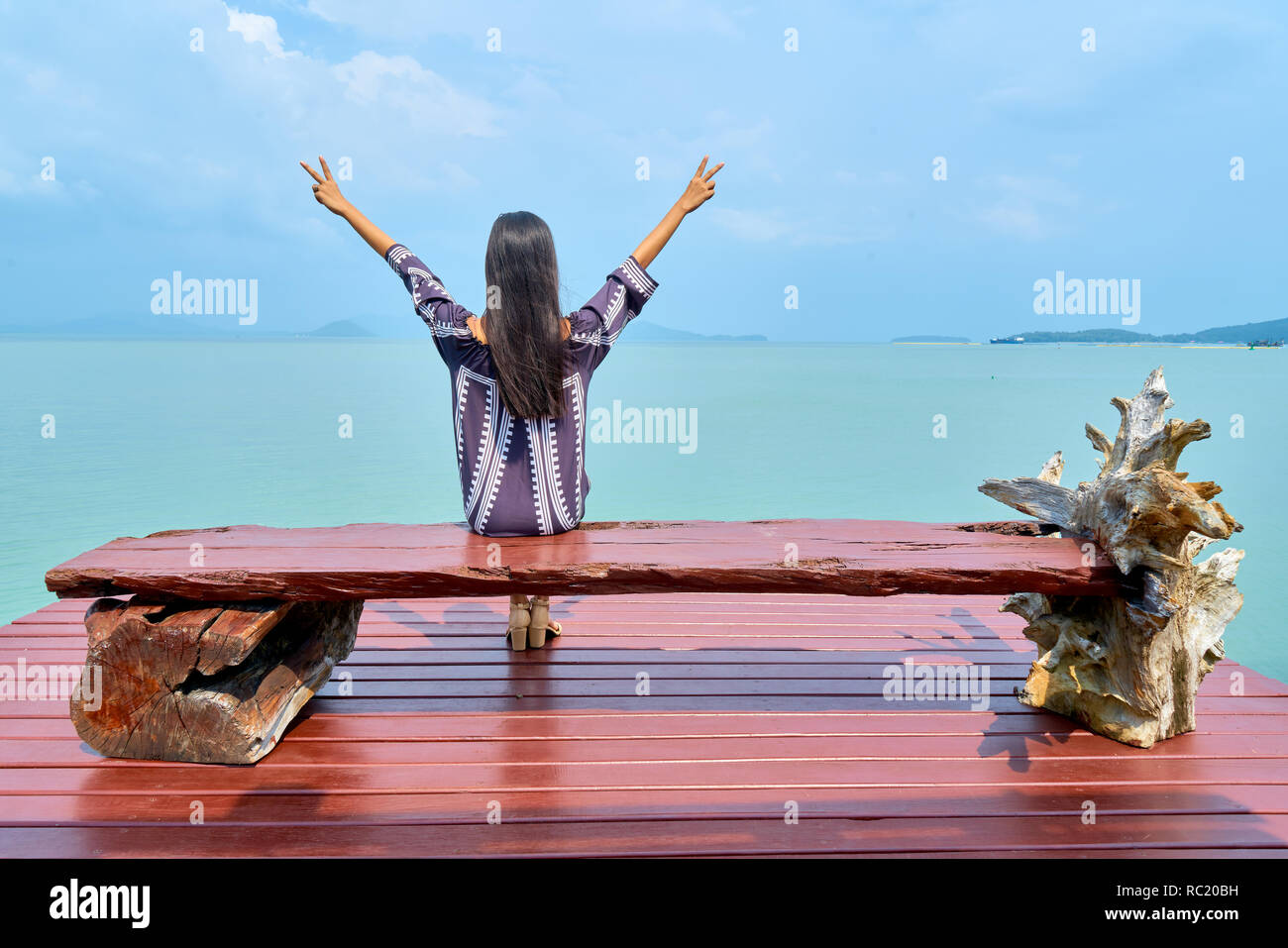Beautiful woman posing - sitting on bench, peace sign gesture and back ...