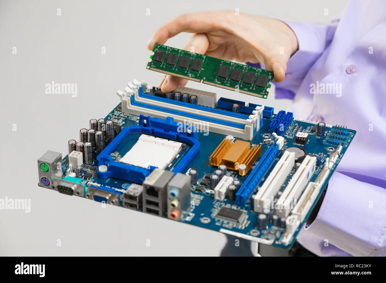 RAM and motherboard in men's hands close-up isolated on light ...