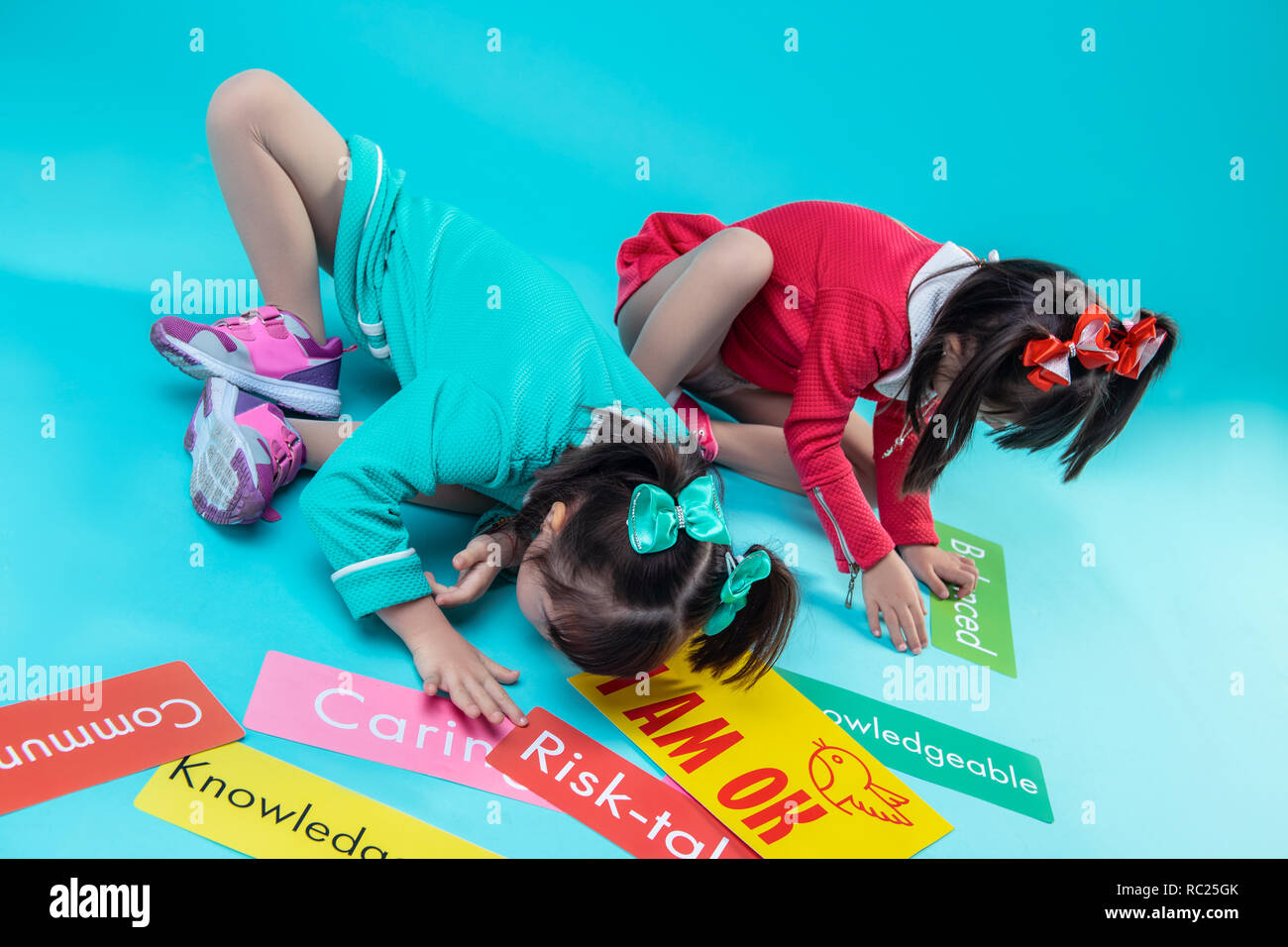 Dark Haired Twin Sisters In Colorful Dresses Sitting Surrounded Stock