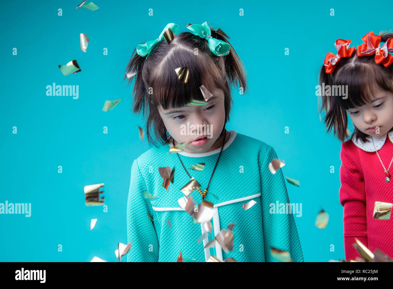 Dark-haired unusual girls with face features standing while confetti ...