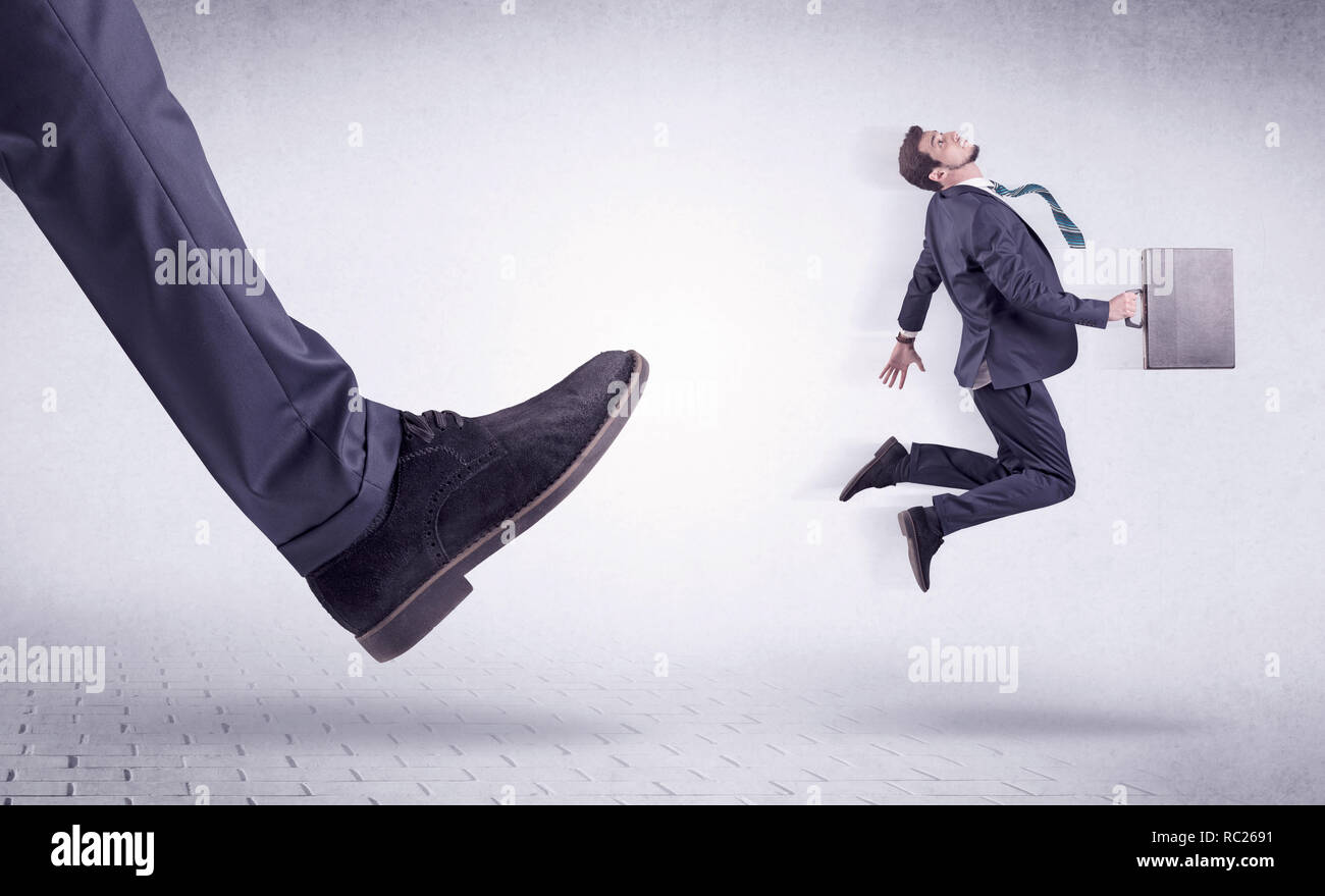 Small young businessman kicked out by a big black shoe Stock Photo - Alamy