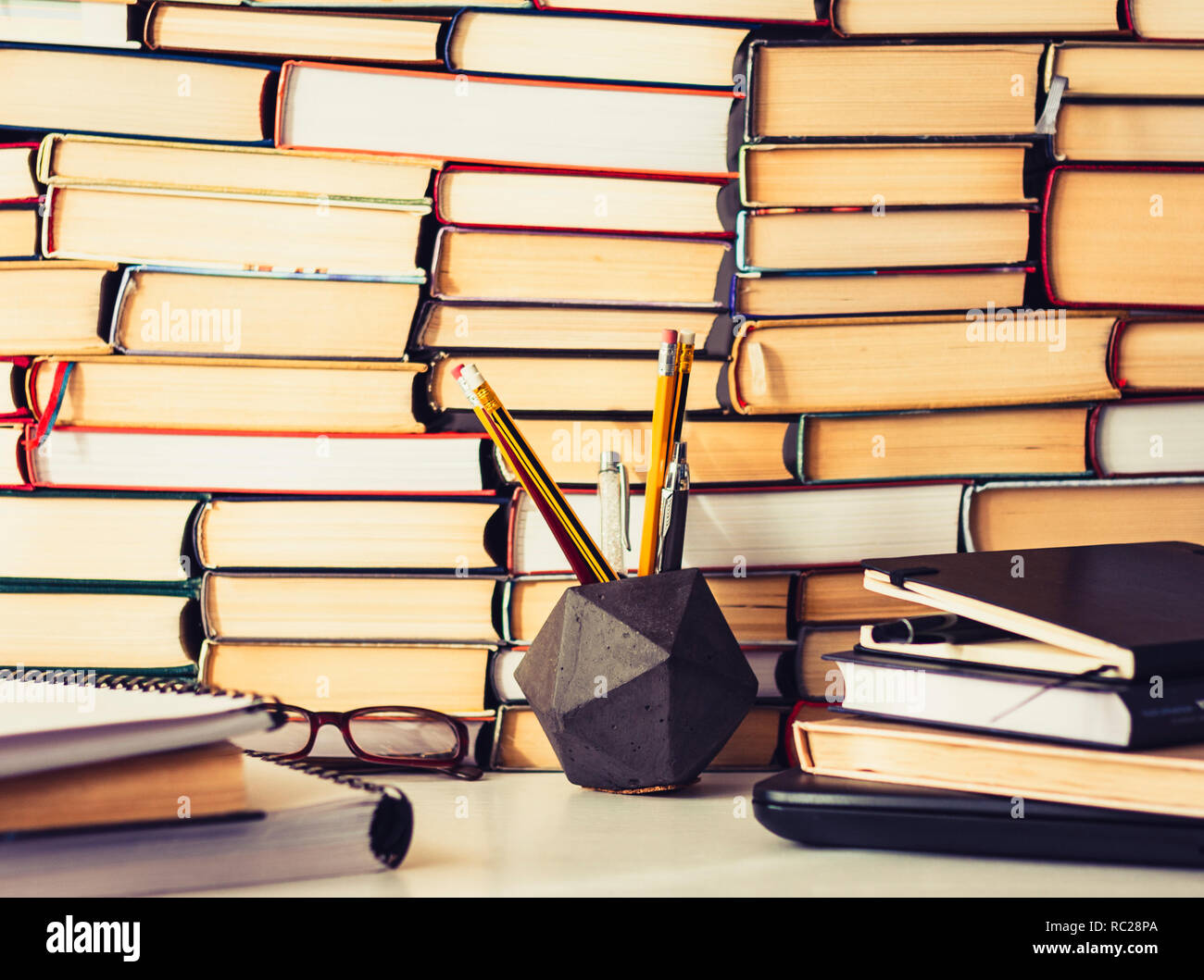 Stack of books, notebook, laptop, glasses in office background for ...