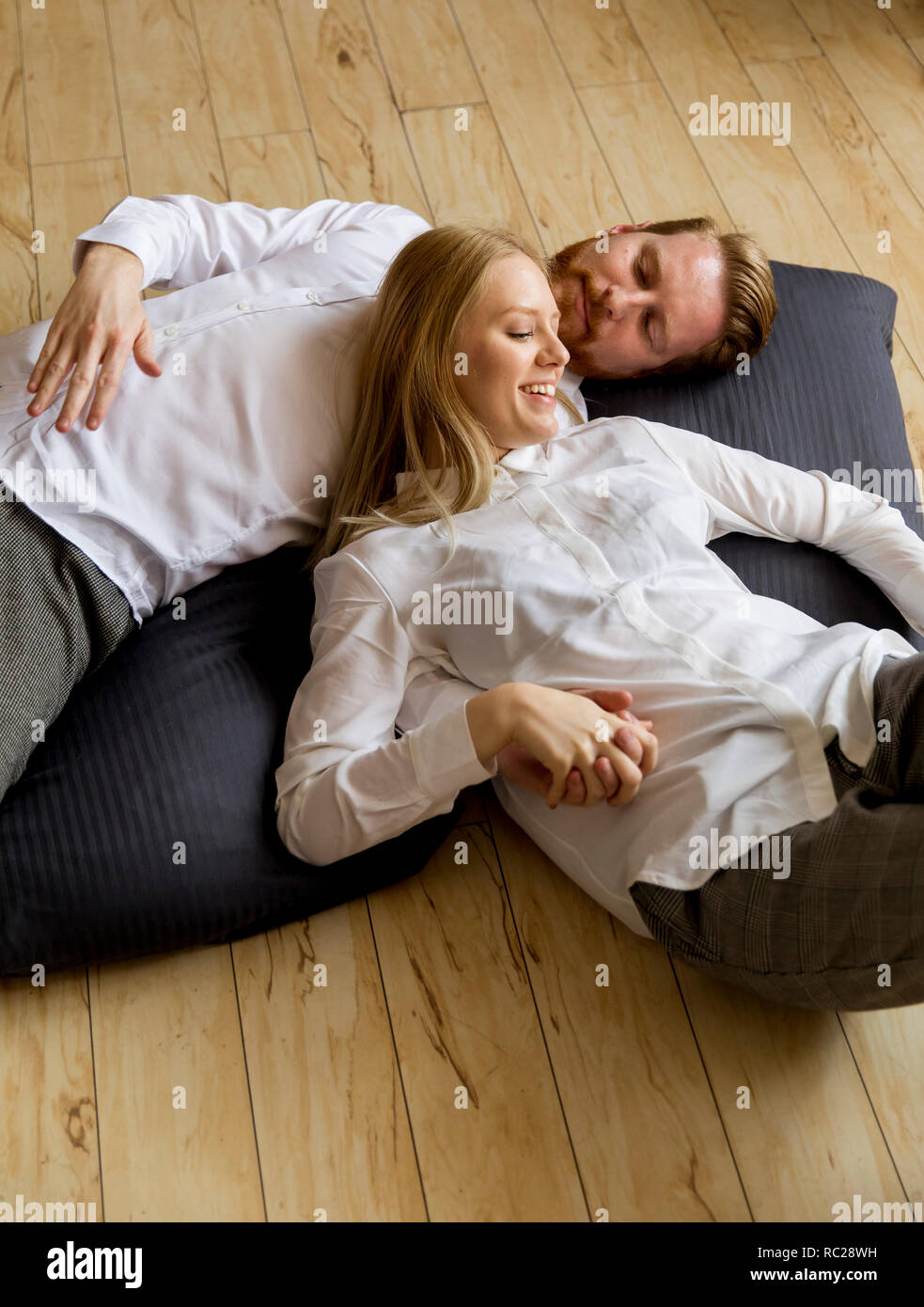 Loving young couple lying and kissing on the floor at home Stock Photo ...