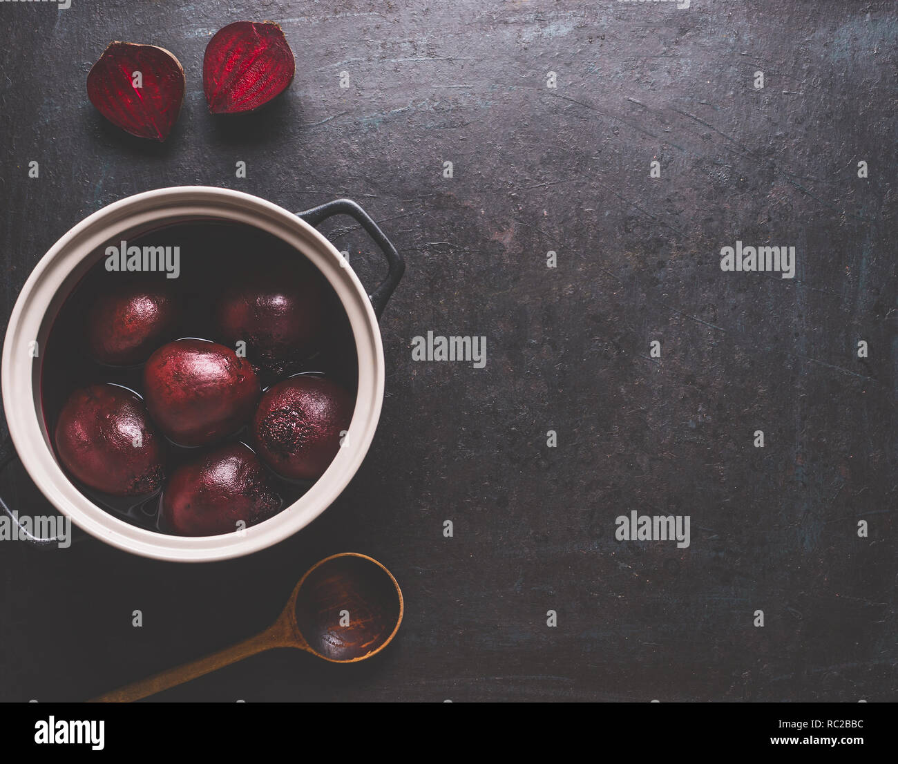Whole boiled beet roots in cooking pot with wooden spoon on dark ...