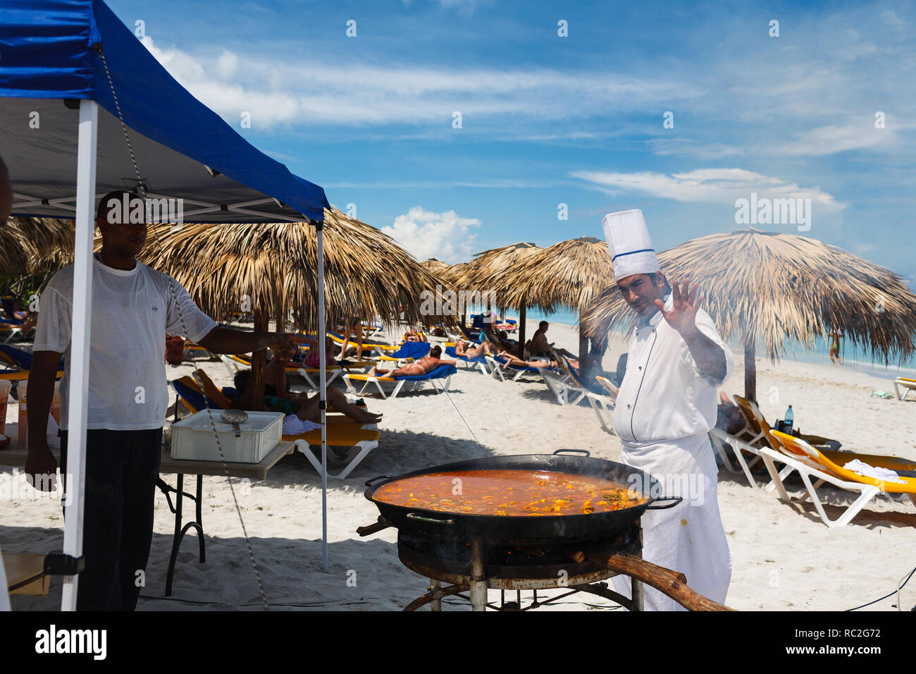 chef prepares a giant seafood paella on beach Varadero near sunbathing ...