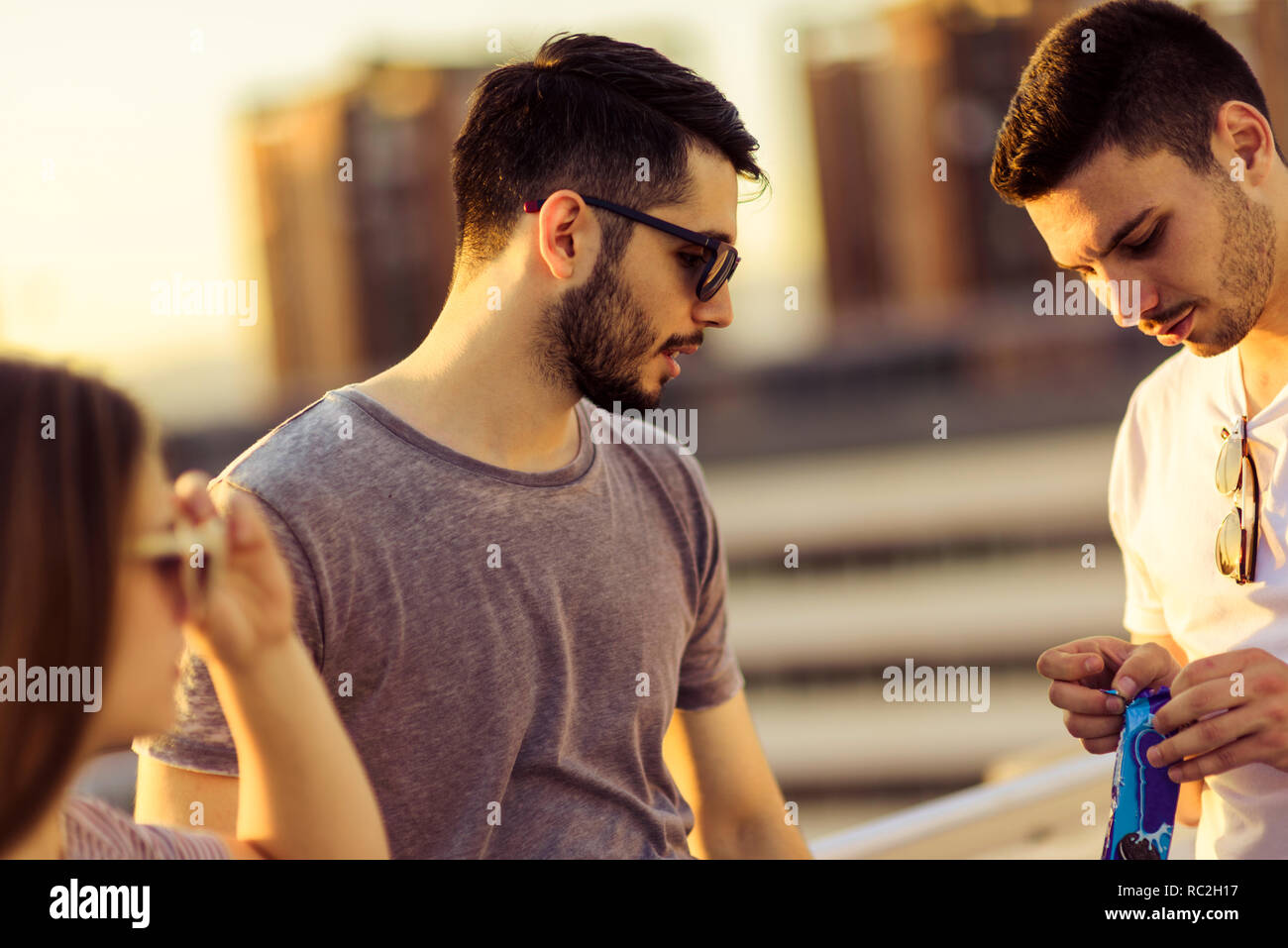 Group of cheerful friends having fun and eating chocolate on balcony ...