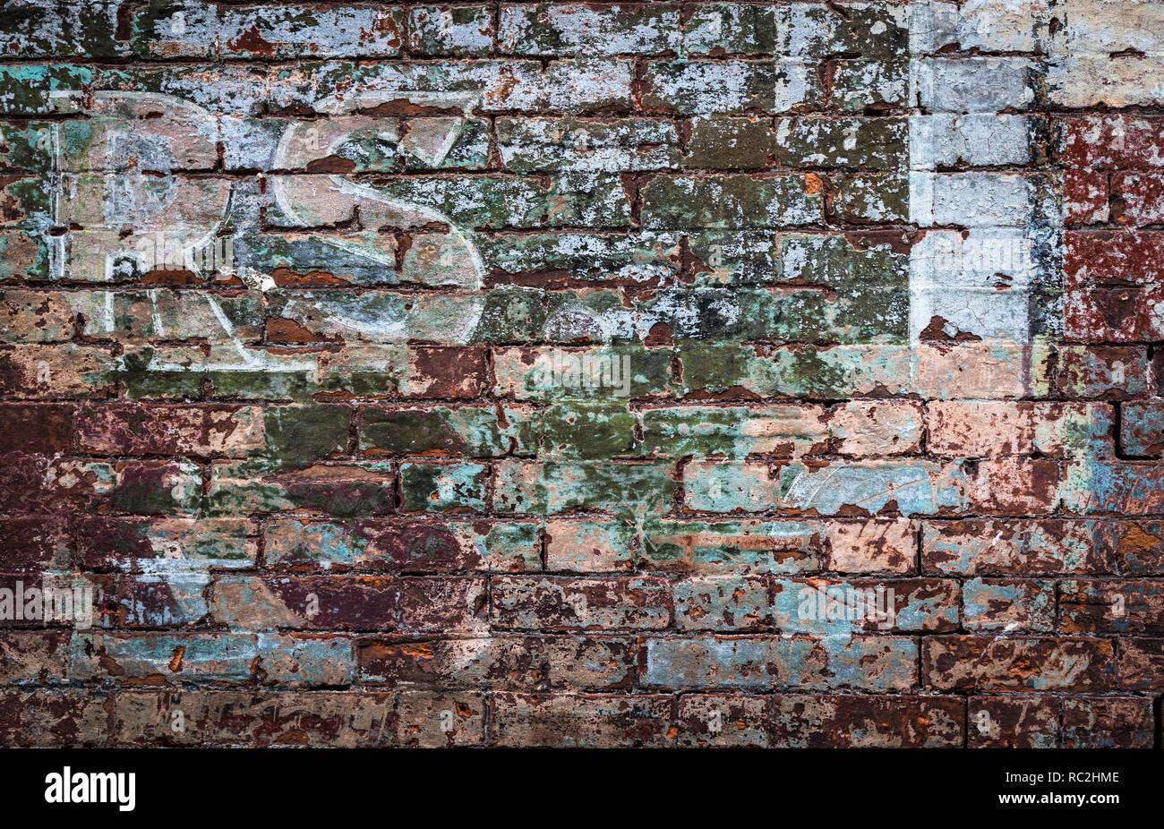 Close-up detail on old faded sign on brick wall of abandoned building ...