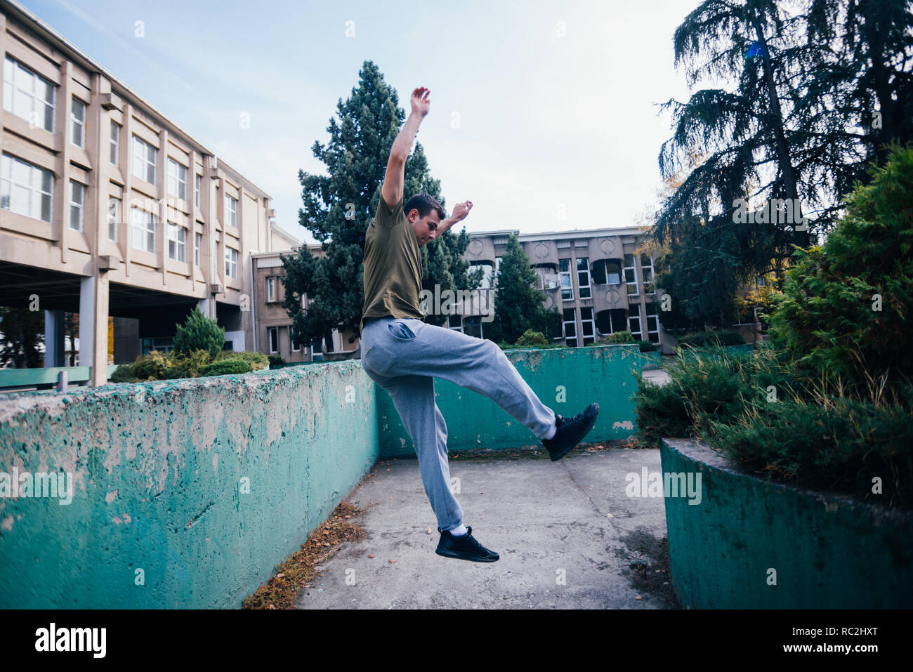 Young parkour guy jumping over a concrete wall and landing on another ...