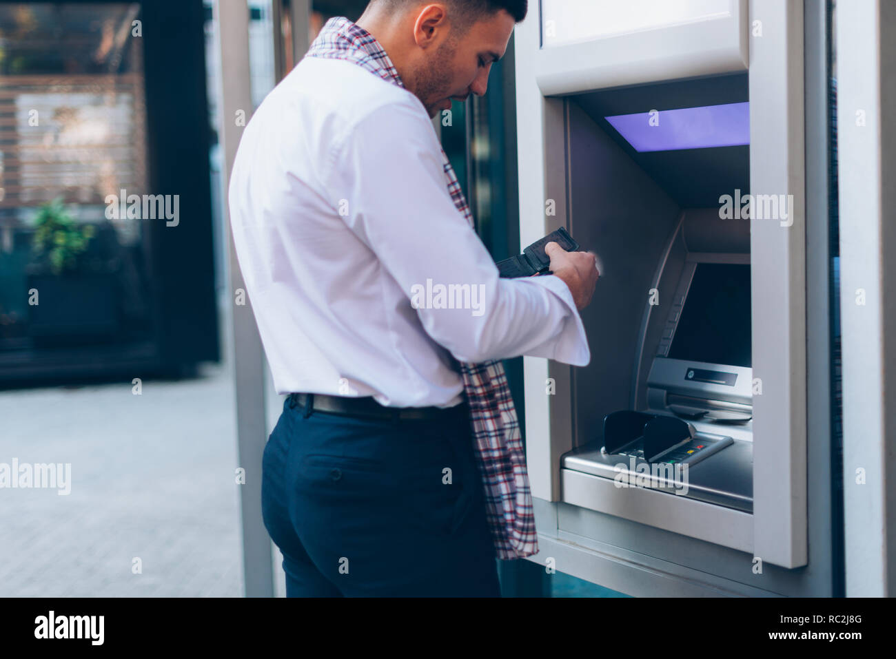 Stylish businessman in white shirt is holding his wallet and standing ...