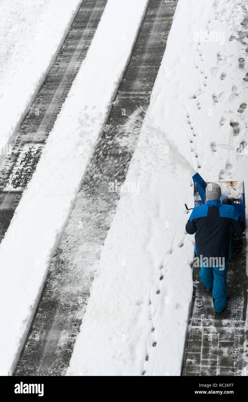 man with a snow blower clears snow from a road after a heavy snowfall ...