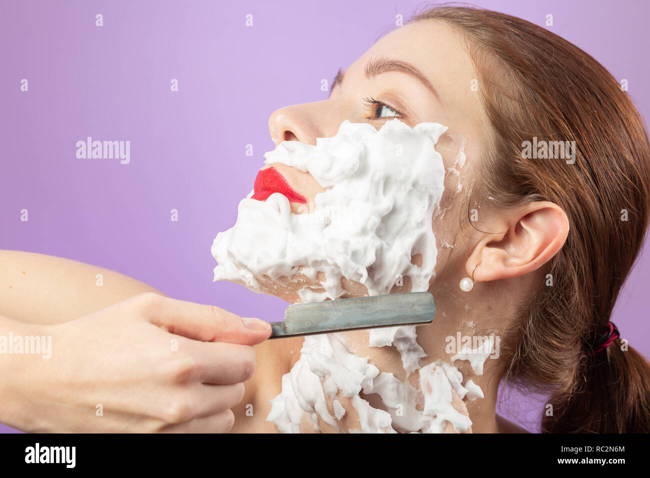 fun young woman has shave with open razor on violet background, side ...