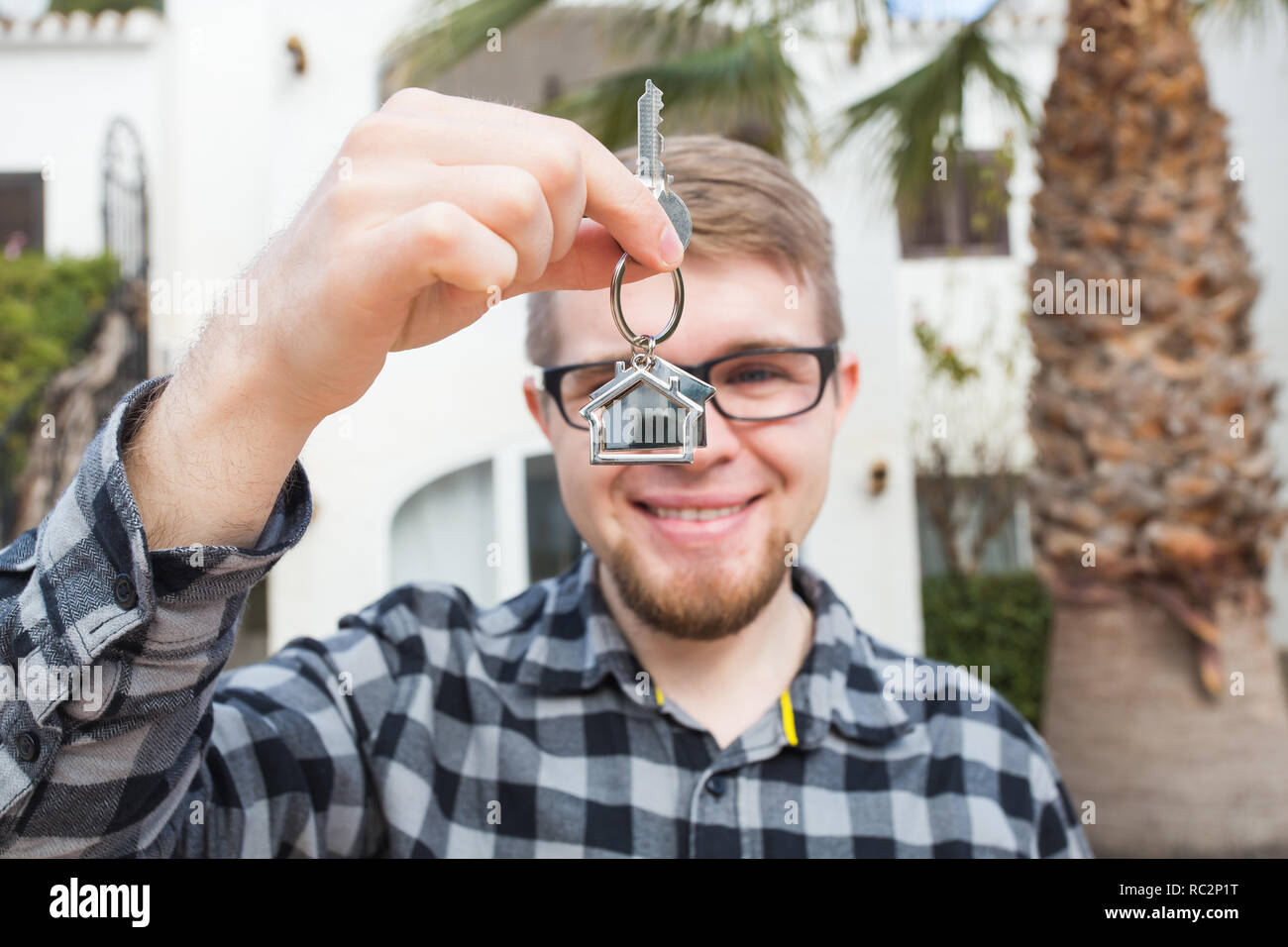 Happy house owner. Smiling young man holding keys and looking at camera ...
