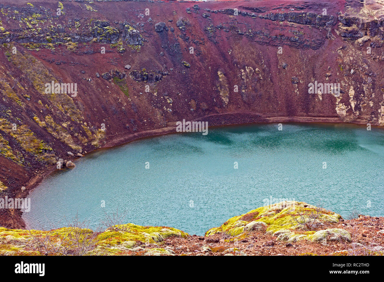 Distinctive red rock and vegetation on one edge of a volcanic crater ...