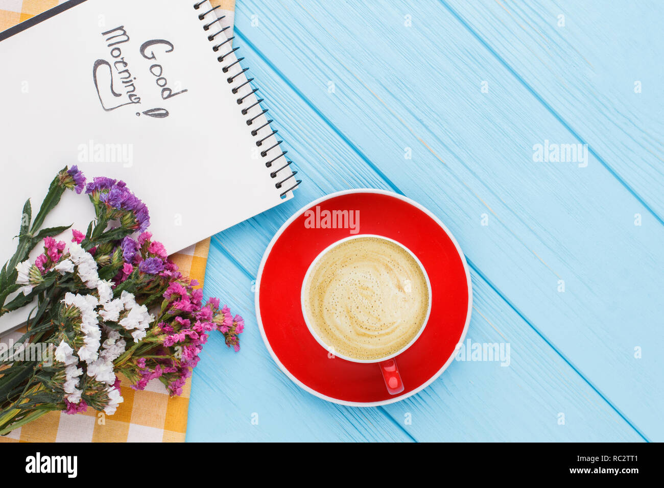 Coffee mug with flowers and notepad with good morning wish. Top view ...