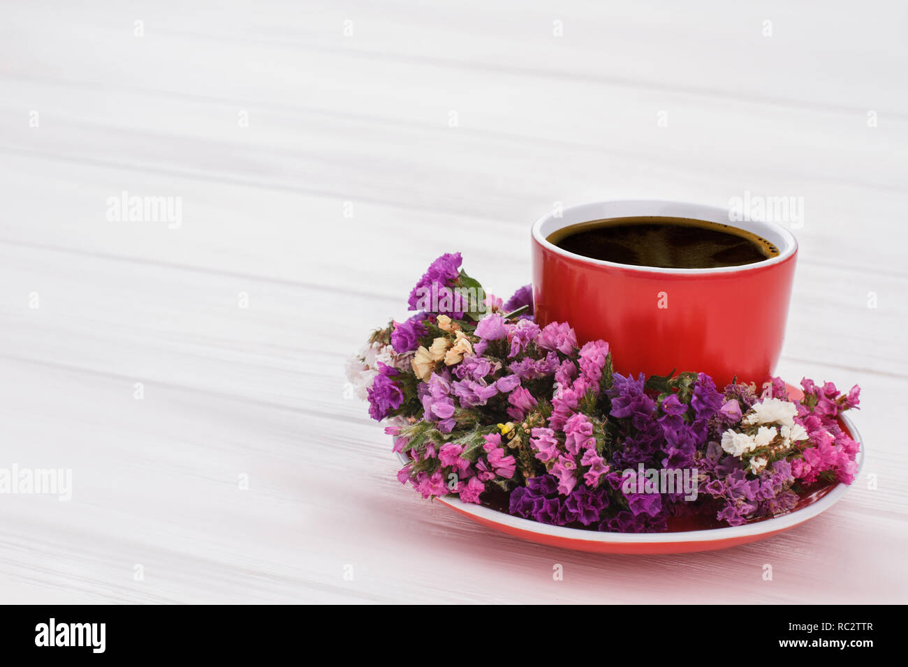 Red coffee and statice limonium flowers. White wooden table background ...