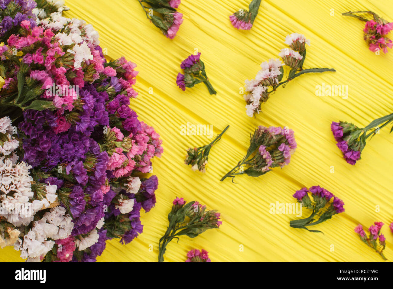 Limonium statice flowers scattered around. Top view. Yellow wood ...